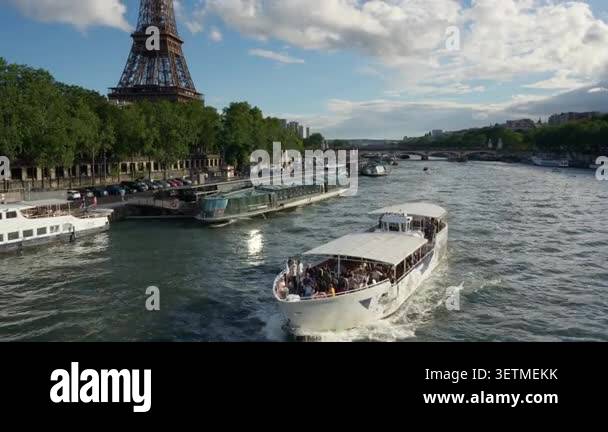 A passenger cruise boat sails along the Seine River near the Eiffel ...