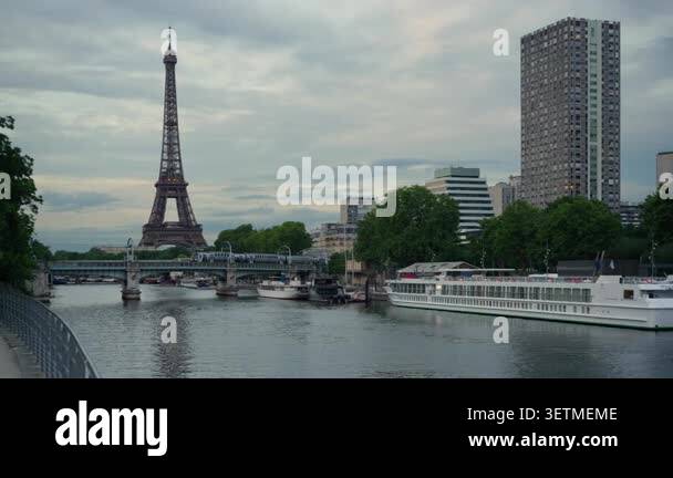 A passenger metro train crosses a river bridge near the Eiffel Tower ...