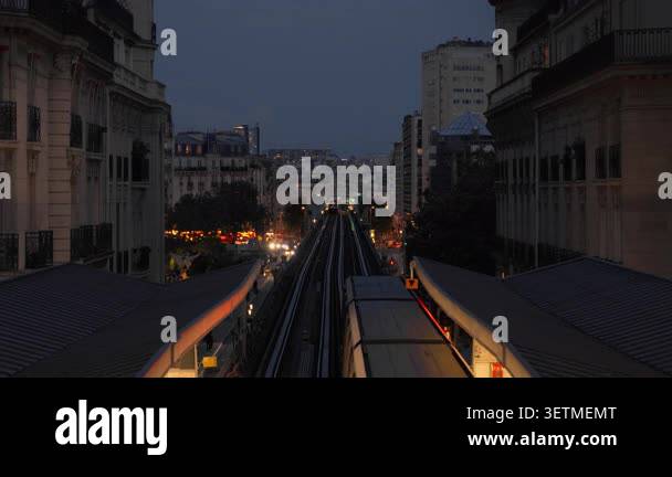 A passenger metro train departs an elevated station and moves along ...