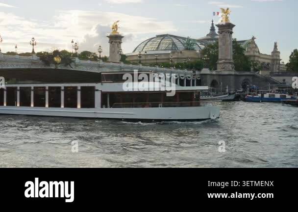 A premium restaurant cruise ship navigates the Seine River past the ...