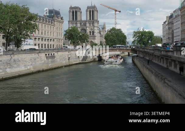 A passenger sightseeing boat with tourists navigates the Seine River ...