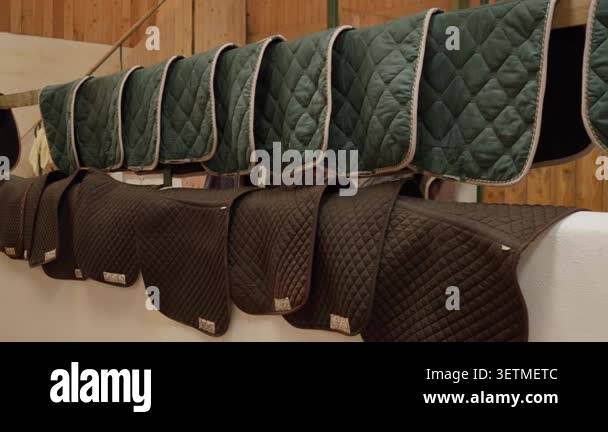 Equestrian saddle pads hanging on storage racks inside a professional ...