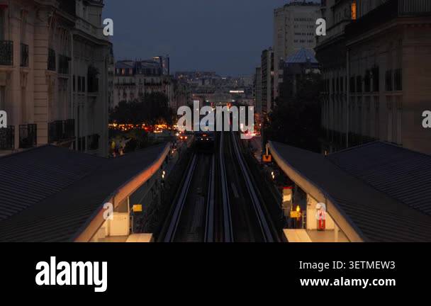 A passenger metro train arrives at an elevated station along urban ...