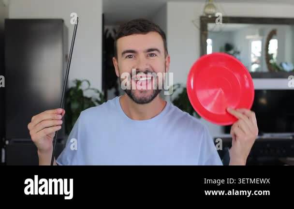 A man is spinning a red plate on a stick, demonstrating a circus skill ...