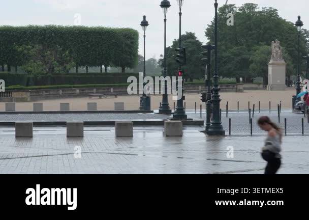 Pedestrians cross a wet street by Place du Carrousel in Paris during ...