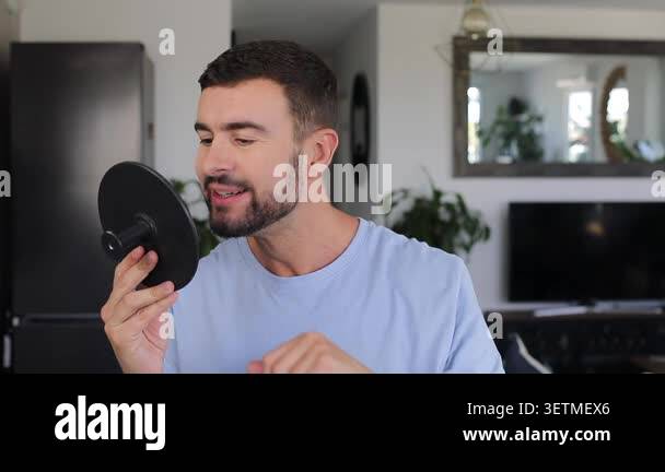 A man is looking into a handheld mirror and checking his appearance ...