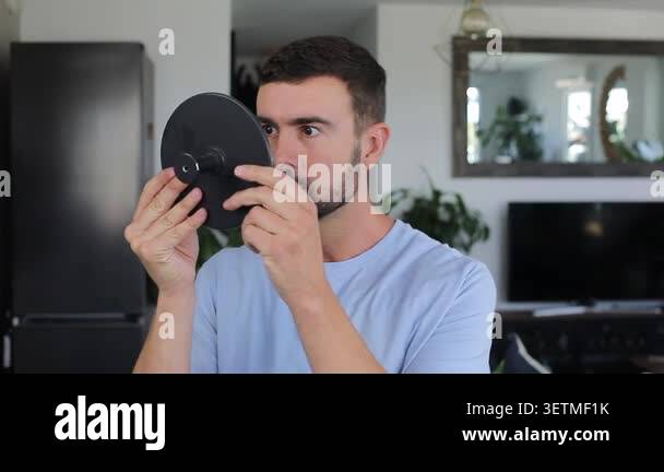 A man is looking into a handheld mirror, checking his appearance and ...