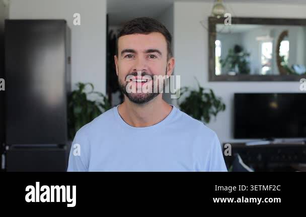 A man smiles and holds up a horseshoe, gesturing with his other hand in ...