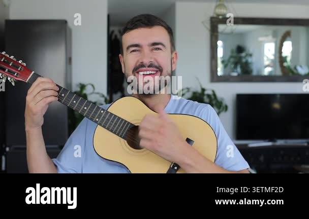 A man is playing an acoustic guitar and singing with enthusiasm in a ...