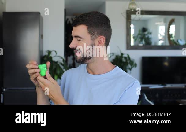 A man is holding a small green container and applying something to his ...