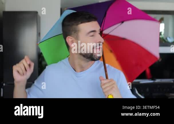 A man with a beard is holding a colorful umbrella and smiling, looking ...