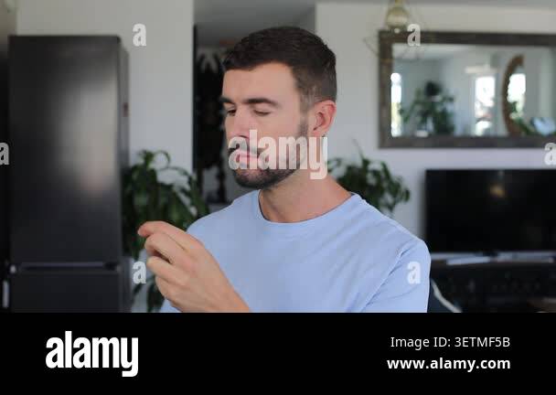 A man is flossing his teeth with dental floss in a well-lit room ...