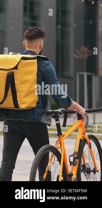 A determined food delivery man rides his bike through the bustling city ...