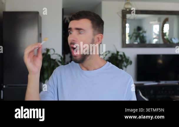 Man with surprised expression holding a lollipop, looking at it closely ...