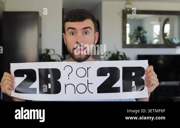 A man holds a sign that reads "2B or not 2B" with a questioning ...