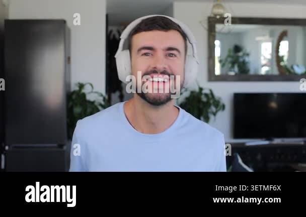 A man wearing headphones is dancing and reacting to music in a living ...