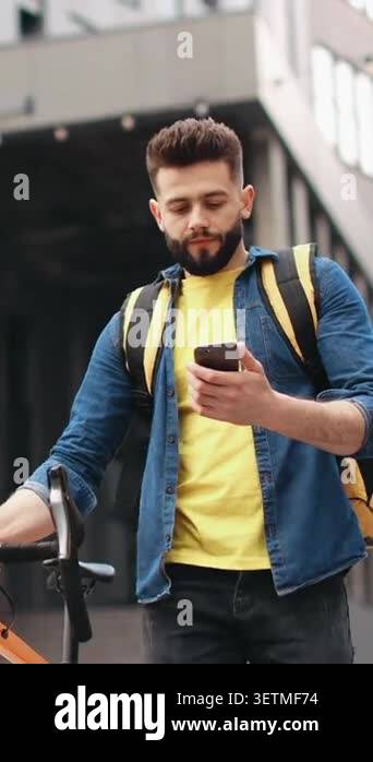 With a serious expression, a delivery man checks his phone while ...