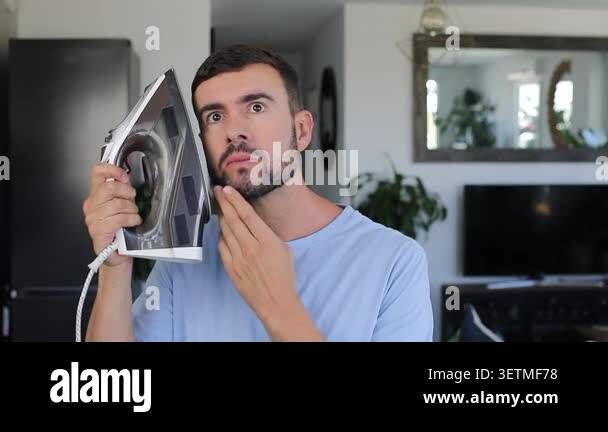 A man holding an iron to his ear, making funny faces and gestures, as ...