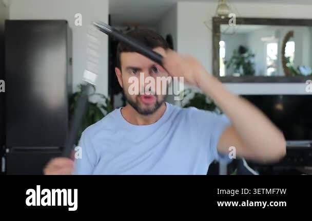 Man with beard in a light blue t-shirt is brushing his hair with a ...