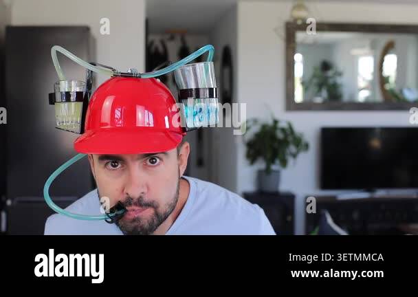 Man wearing a novelty drinking helmet with tubes and cups, looking ...