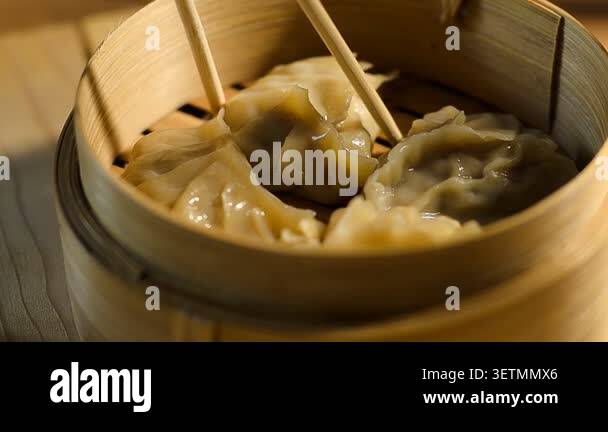 Steamed gyoza dumplings in bamboo steamer with chili sauce on rustic ...