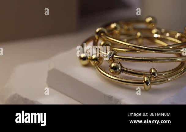 A golden bracelet shines on a plain background. The camera focuses on ...
