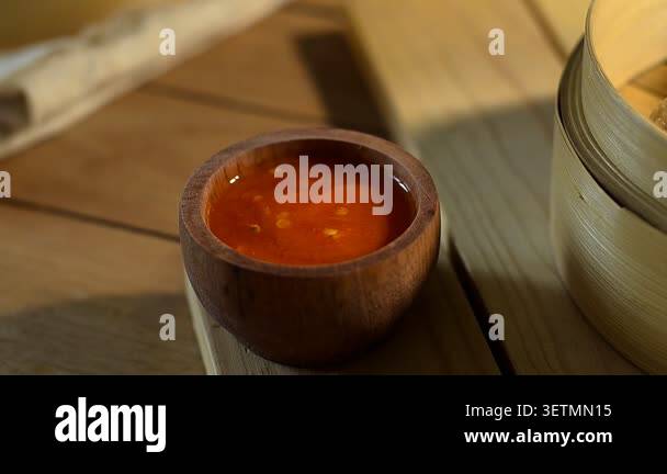 Steamed gyoza dumplings in bamboo steamer with chili sauce on rustic ...