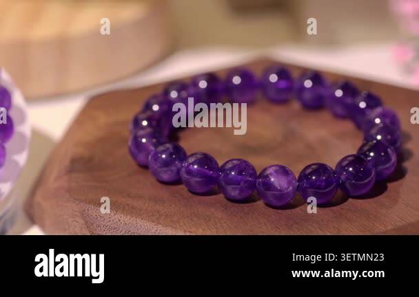 Amethyst bracelet is placed on a wooden tray. The focus is on the stone ...