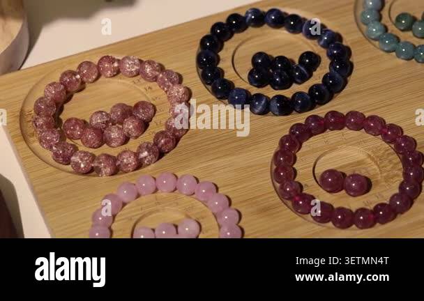 Six natural stone bracelets are placed on a wooden tray. Each bracelet ...