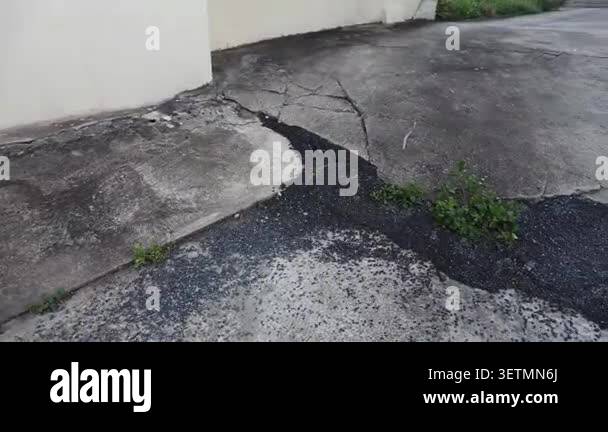 The camera shows cracks in the concrete of a parking area. The cracks ...