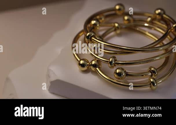 A close view of a golden bracelet shows its unique design with round ...