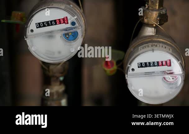 Close-up of two indoor water meters with white faces and red digits ...