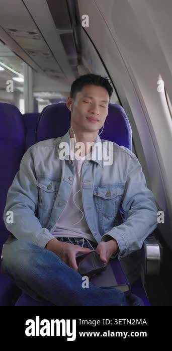 A cheerful young male passenger sitting comfortably by the window seat ...