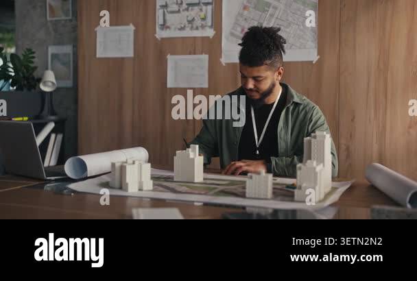 A designer creates a city model on a table in an office. Plans and maps ...