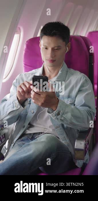 A cheerful young male passenger sitting comfortably by the window seat ...