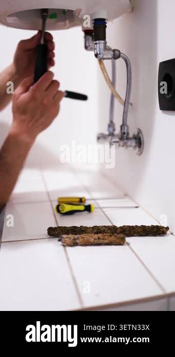 Person handling some pipes of an electric water heater with a wrench ...
