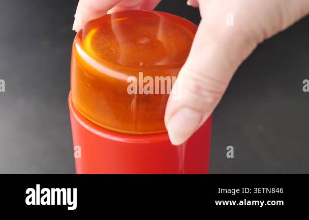 A hand turns an orange manual grinder while coffee grounds and ...
