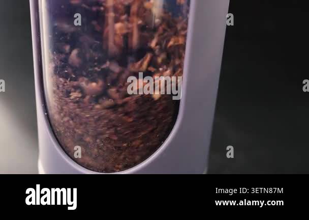 Roasted coffee beans spinning in a transparent grinder bowl on a dark ...