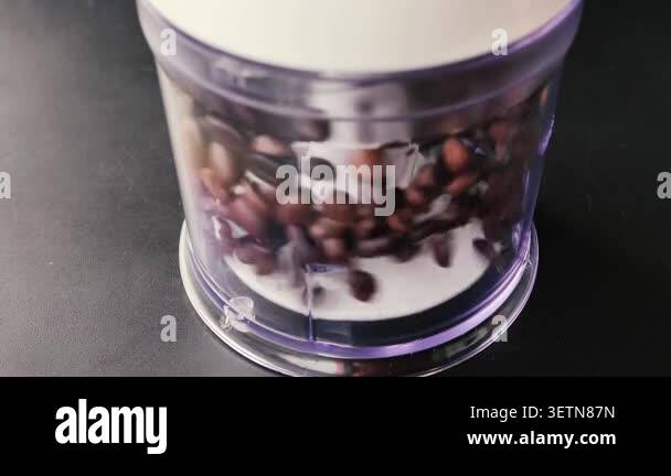 Roasted coffee beans spinning in a transparent grinder bowl on a dark ...