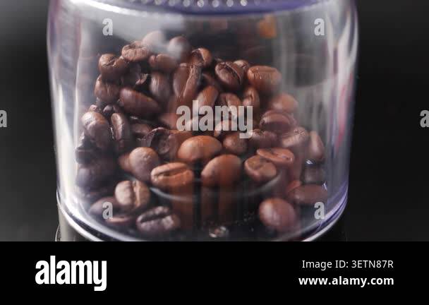 A macro close-up image of roasted coffee beans in a coffee machine or ...