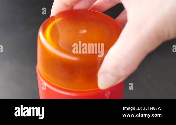 A hand turns an orange manual grinder while coffee grounds and ...