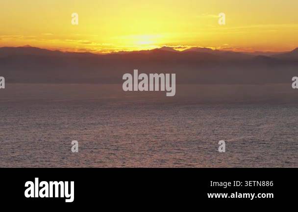 Sunset over calm ocean with distant mountain horizon Stock Video ...