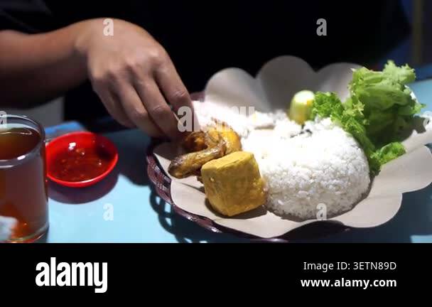 Traditional Indonesian meal serving warm white rice with crispy fried ...