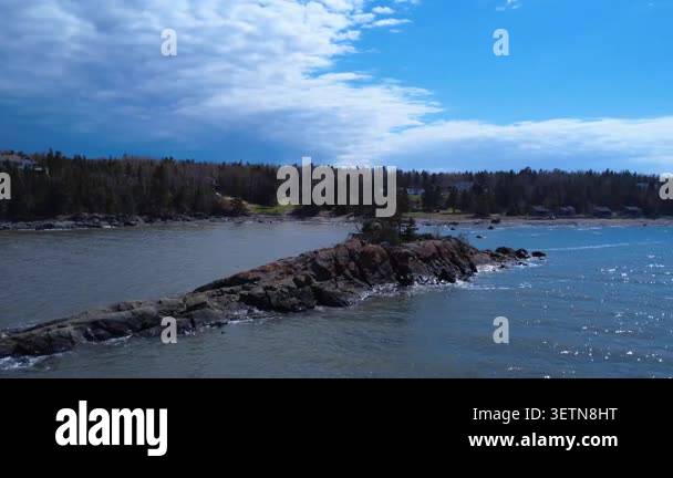 Aerial exploration of a rocky island where a few fir trees thrive amid ...