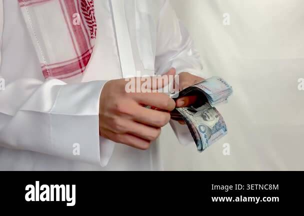 Saudi man wearing traditional thobe counting five hundred riyal ...