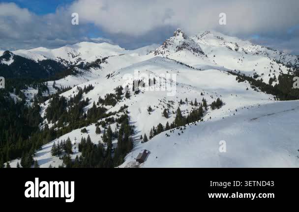 Scenic aerial drone shot of the Ciucas mountain hut surrounded by snow ...