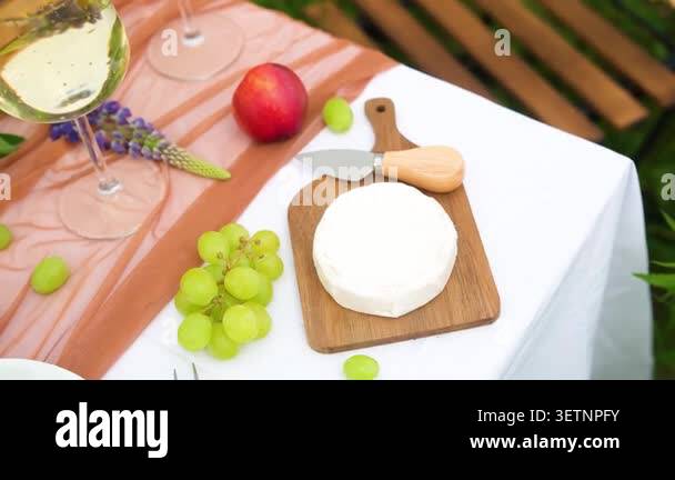 Picnic table with cheese, grapes, and fruit in outdoor setting Stock ...