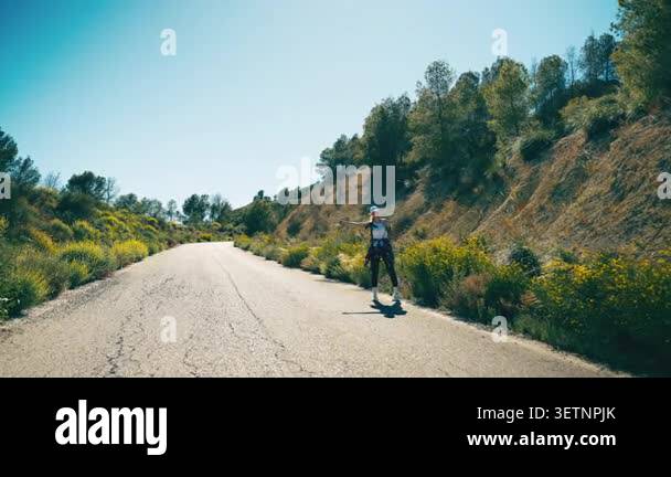 Free spirited woman with a backpack walking along a mountain road and ...