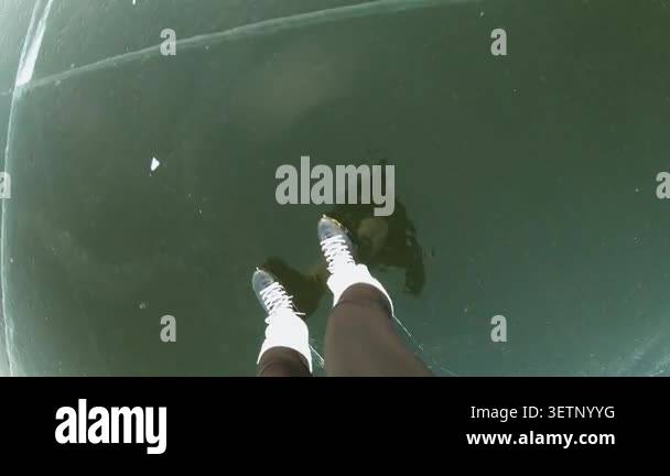Female feet of skater in figure skates sliding on ice surface of river ...