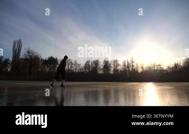 Girl in figure skates is skating on ice surface at sunset time. Young ...